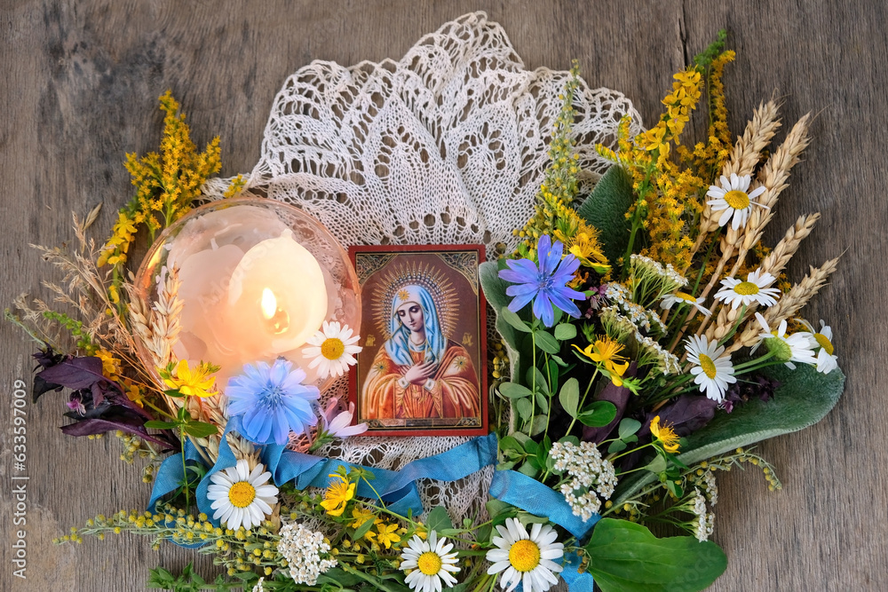 old orthodox icon with Our Lady image, candle, sacred herbs and flowers ...