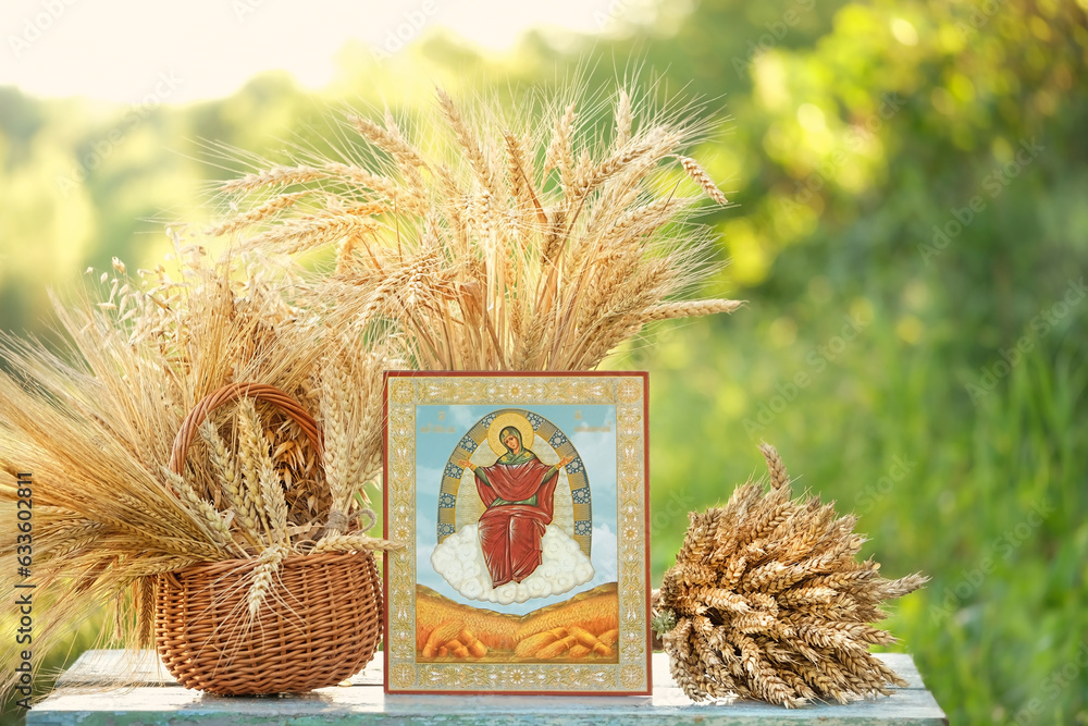 old orthodox icon with Our Lady image and ripe grain ears on table in ...