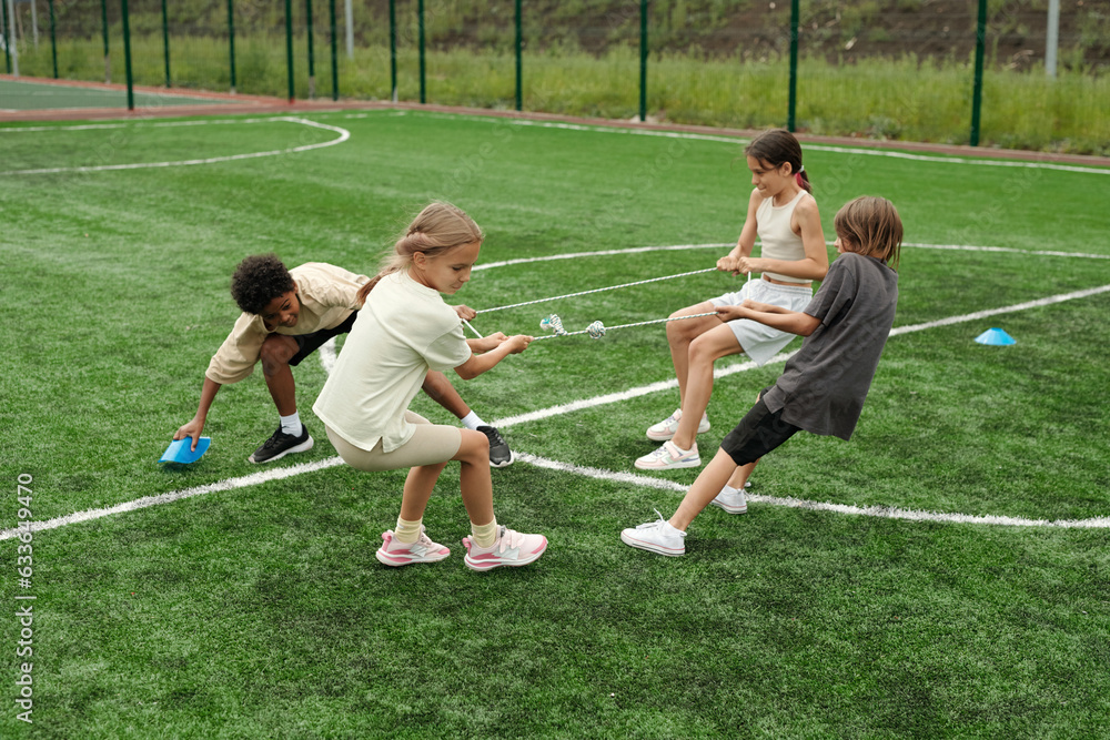 Foto de Team of four secondary school children pulling rope during ...