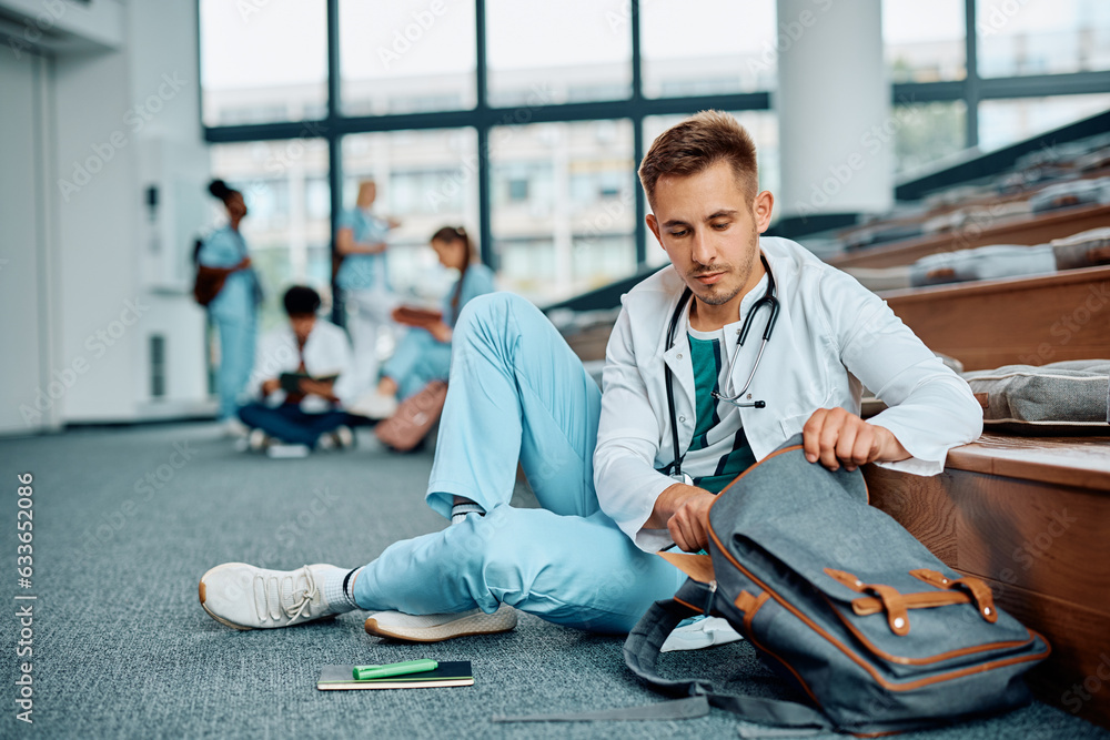 Medical student packing his backpack after learning in amphitheater at ...
