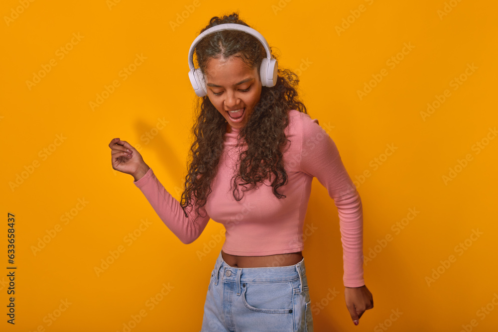 Young cheerful ethnic Indian woman zoomer in headphones is dancing ...