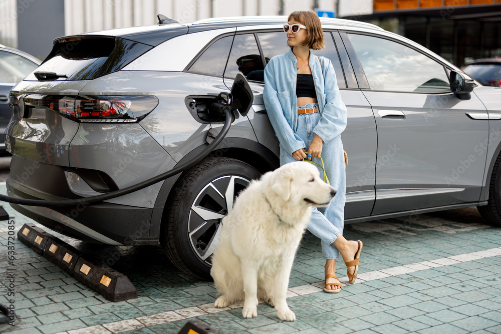 Young woman with a huge white dog waiting for electric car to be ...