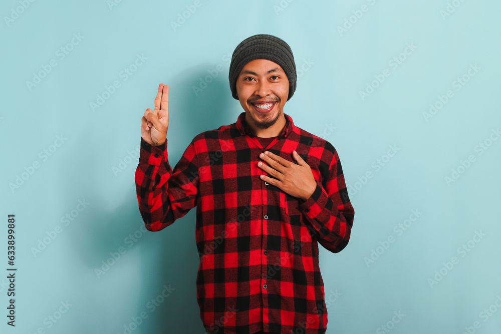 A young Asian man with a beanie hat and red plaid flannel shirt is ...