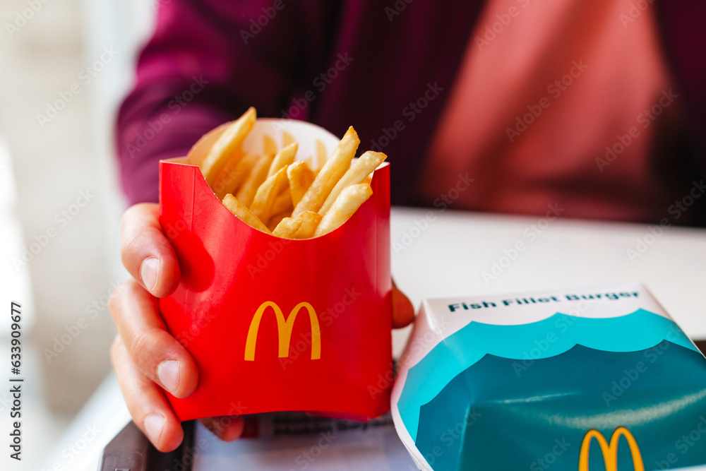 Hands hold a package of French fries at McDonald's. Stylish light ...