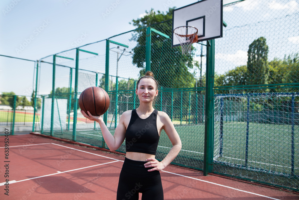Young sports girl with a basketball on the basketball court outdoors ...