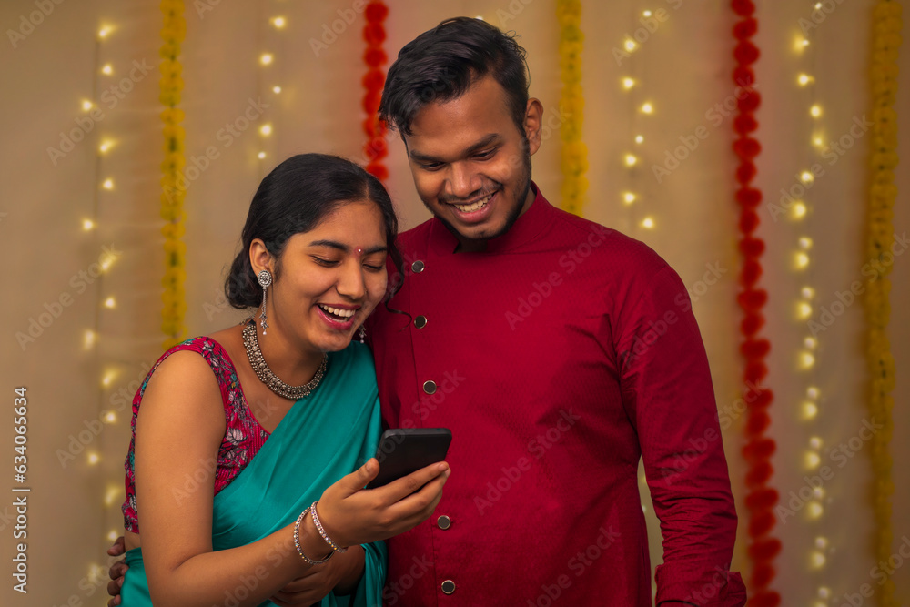 Indian couple using mobile phone while celebrating diwali at home Stock ...