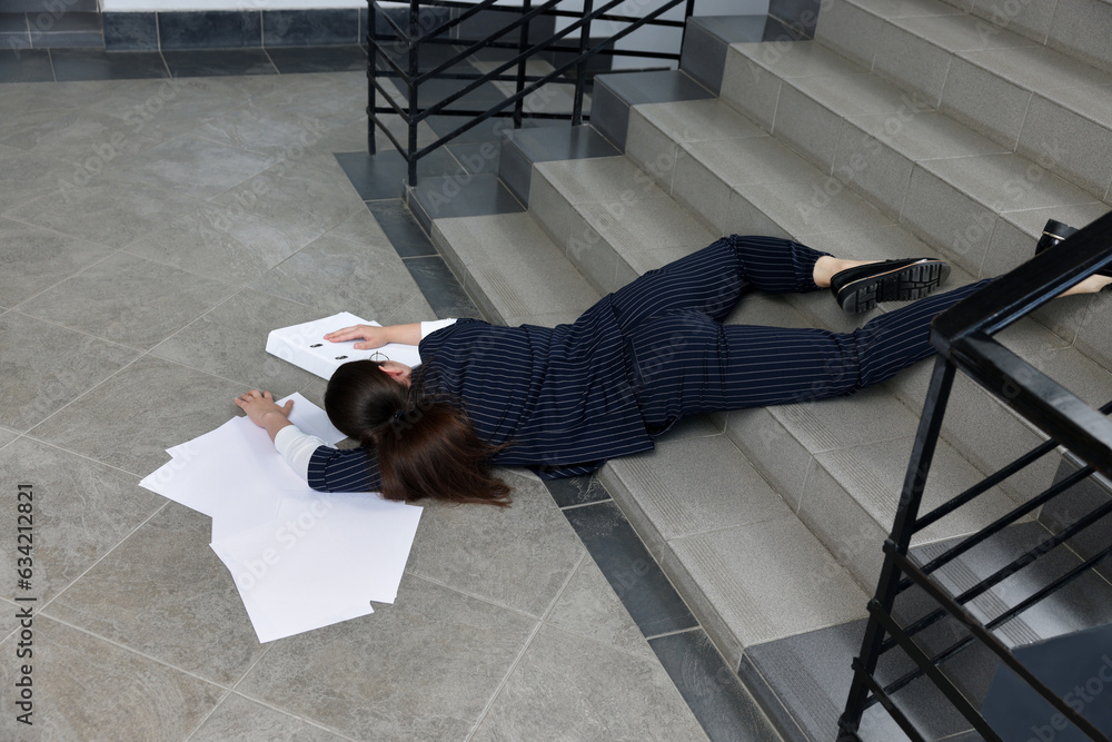 Unconscious woman with scattered folder and papers lying on floor after ...