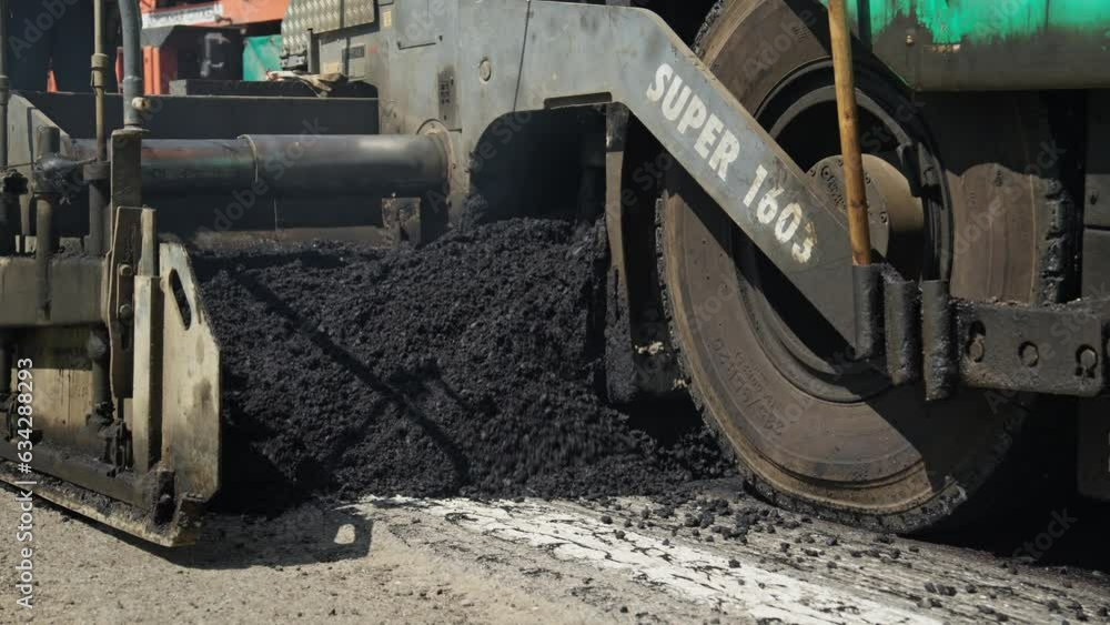 Roadway repair. Machine is pouring hot fresh asphalt for road ...