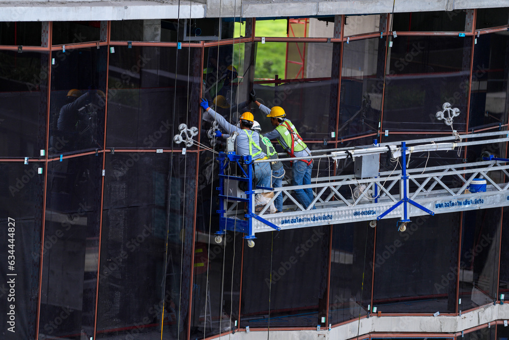 workers install material of glass wall on facade structure building ...