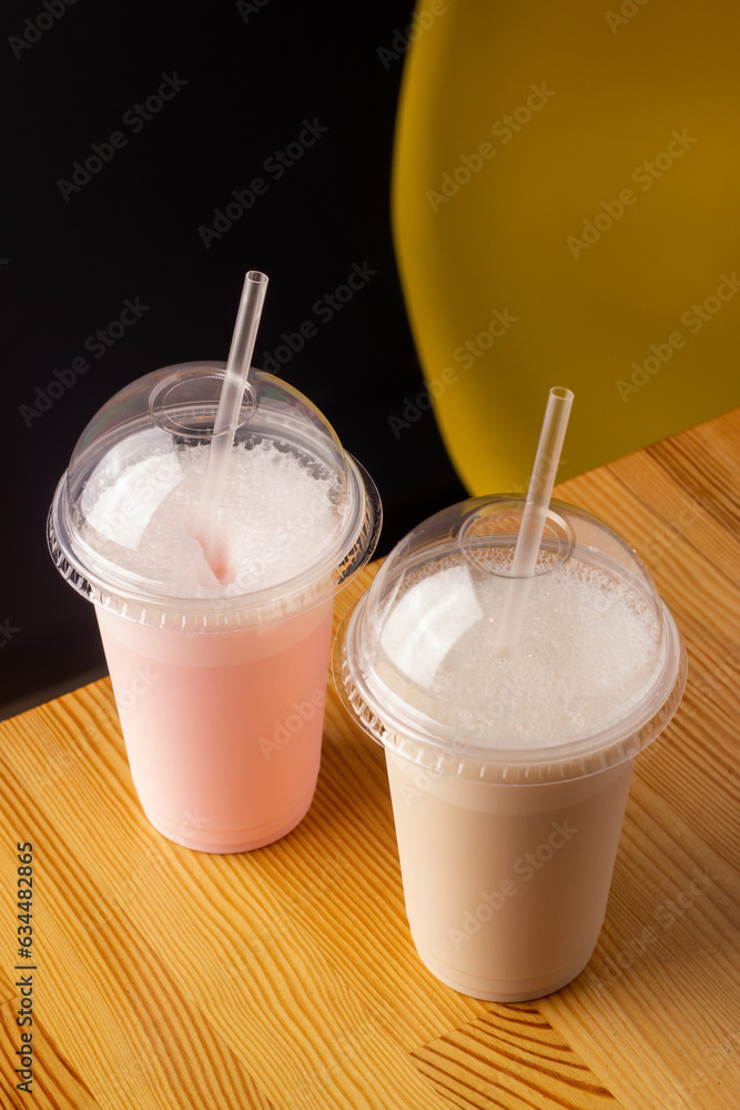 Two milkshakes in plastic glasses with plastic lids and tubes. Delicate ...