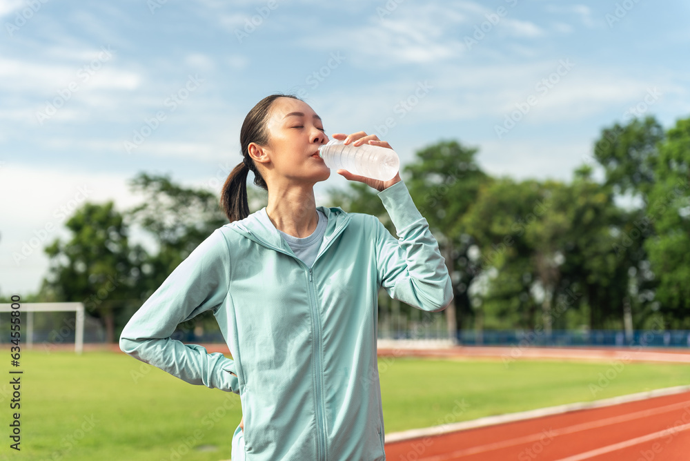 Beautiful asian woman drinking water from bottle after running with ...