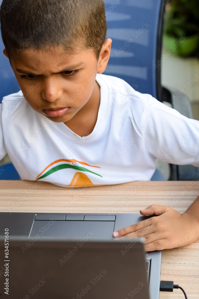 Little boy sitting at table using laptop for online class in Grade 1 ...