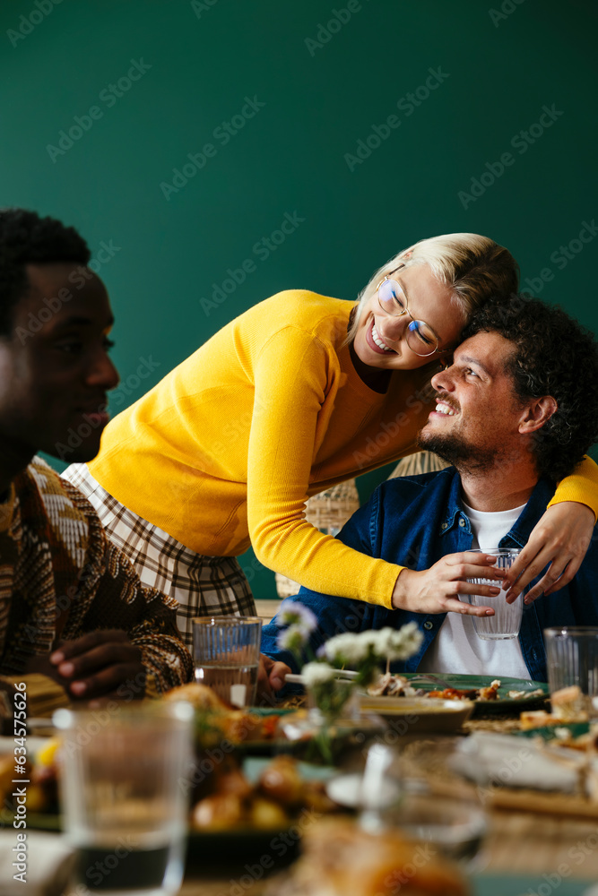 Smiling woman hugging friend at dining table Stock Photo | Adobe Stock