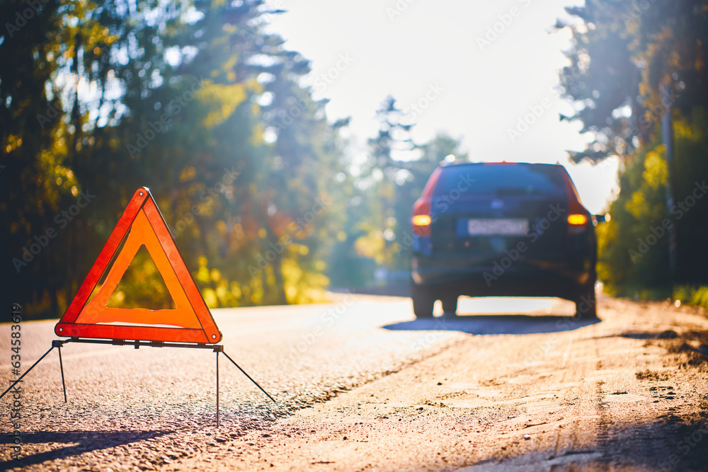 Red emergency stop sign on road. Blurred broken down car with warning ...
