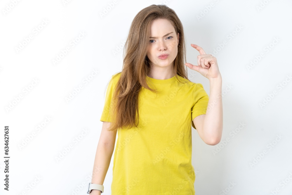 Displeased Young beautiful girl wearing yellow T-shirt shapes little ...