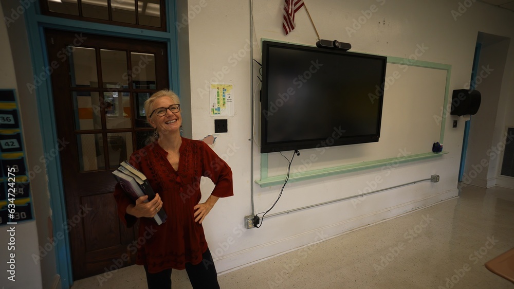 Portrait of smiling happy teacher entering an empty classroom, turning ...