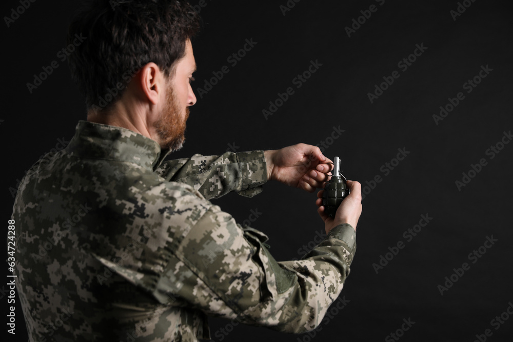 Soldier pulling safety pin out of hand grenade on black background ...