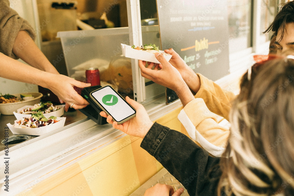 Woman paying via tap to pay method through smart phone while buying ...