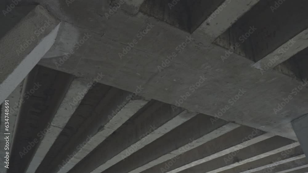 Large dark cement bridge construction from beneath at daytime. Beam ...