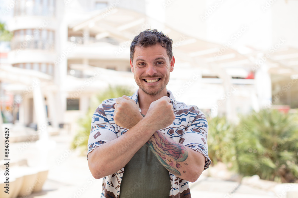 handsome man smiling cheerfully and celebrating, with fists clenched ...