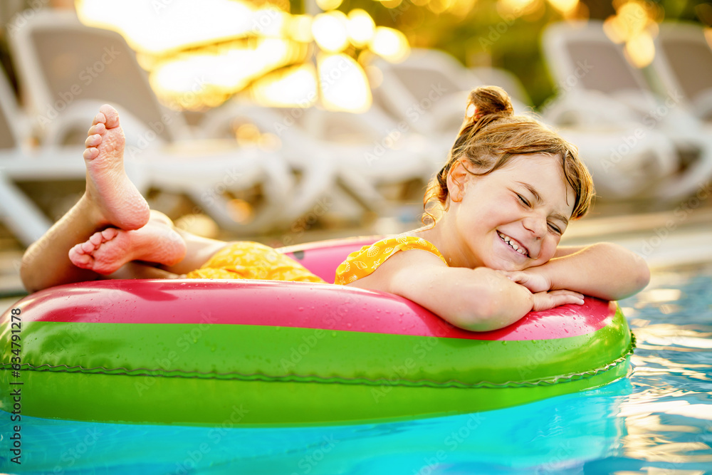Happy little girl with inflatable toy ring float in swimming pool ...