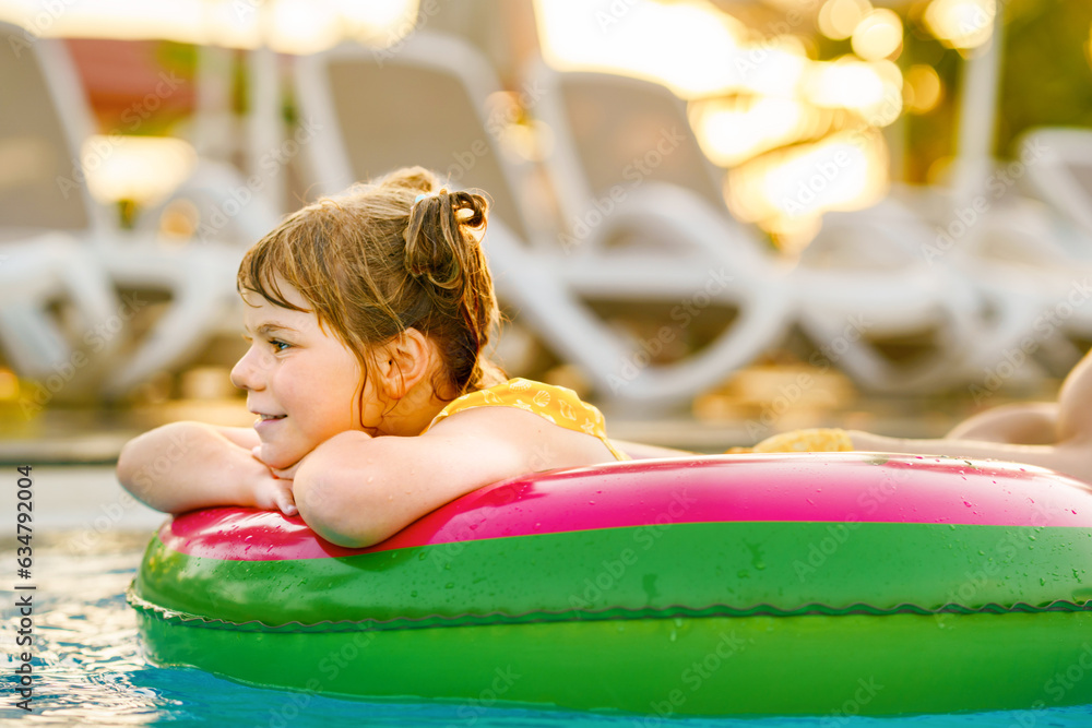 Happy little girl with inflatable toy ring float in swimming pool ...