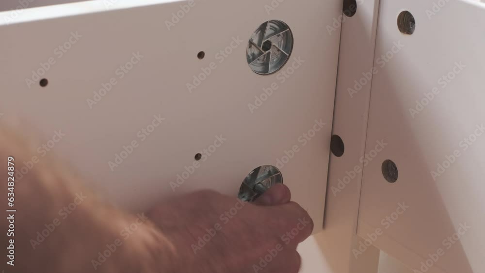 assembling a New wooden bed in Bedroom. Man tighten by hex key the ...