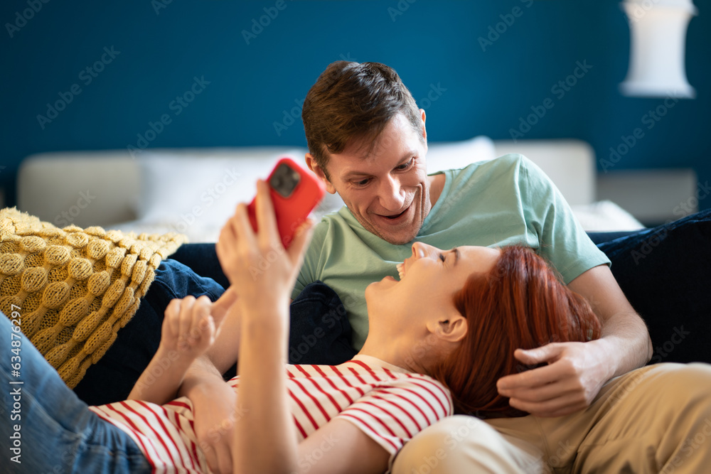 Positive middle aged couple laughing looking each other while relaxing ...