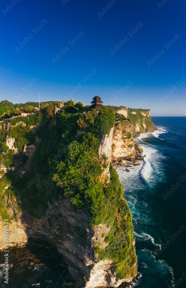 At the foot of imposing cliffs, waves surge with fervent energy, their ...