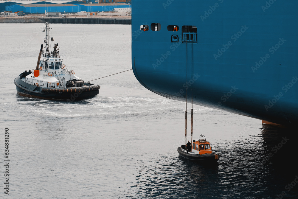 Mooring operation. Docking of the cargo vessel in the port. Tug boat ...