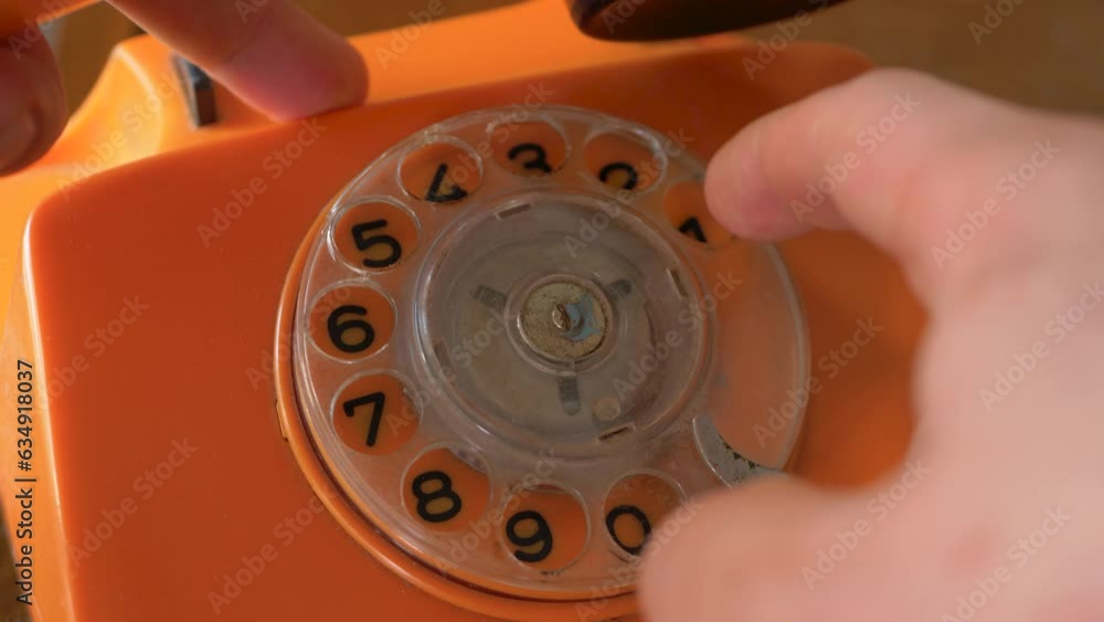Typical old phone with letters on its rotary dial. Orange color ...