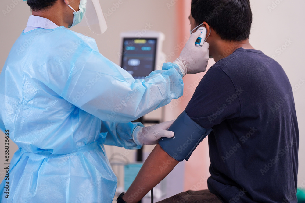 Asian young staff wear PPE protection suit using thermometer with blood ...