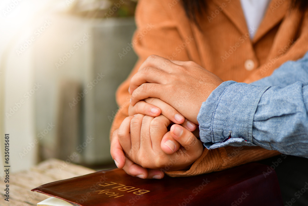 Couple are pray together, hands in prayer together over an open Holy ...