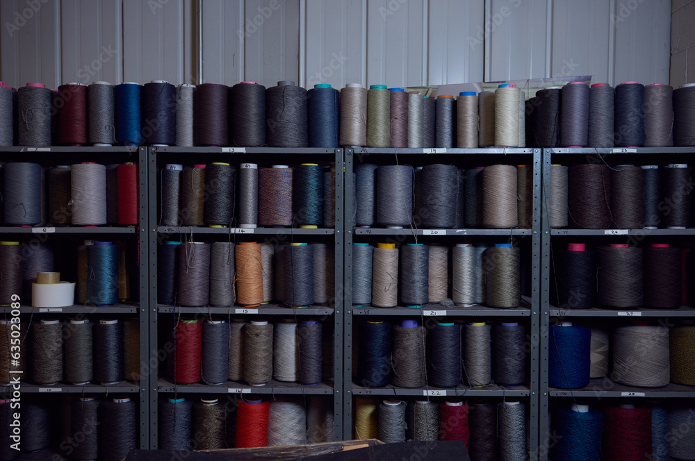 Raw spindles of industrial cotton on a weaving factory shelf, hand ...