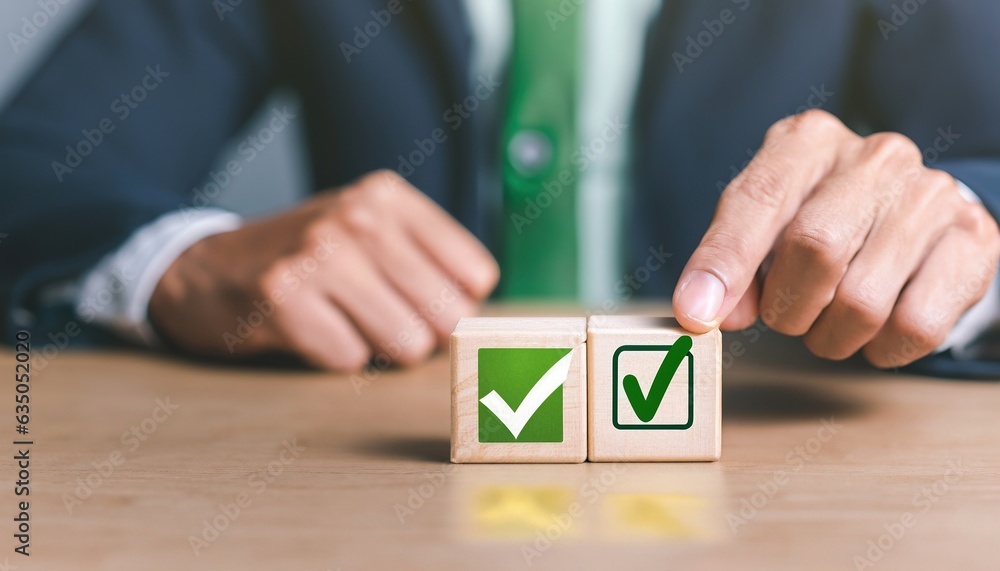 Wooden blocks checklist and green check mark icon with hand on table ...