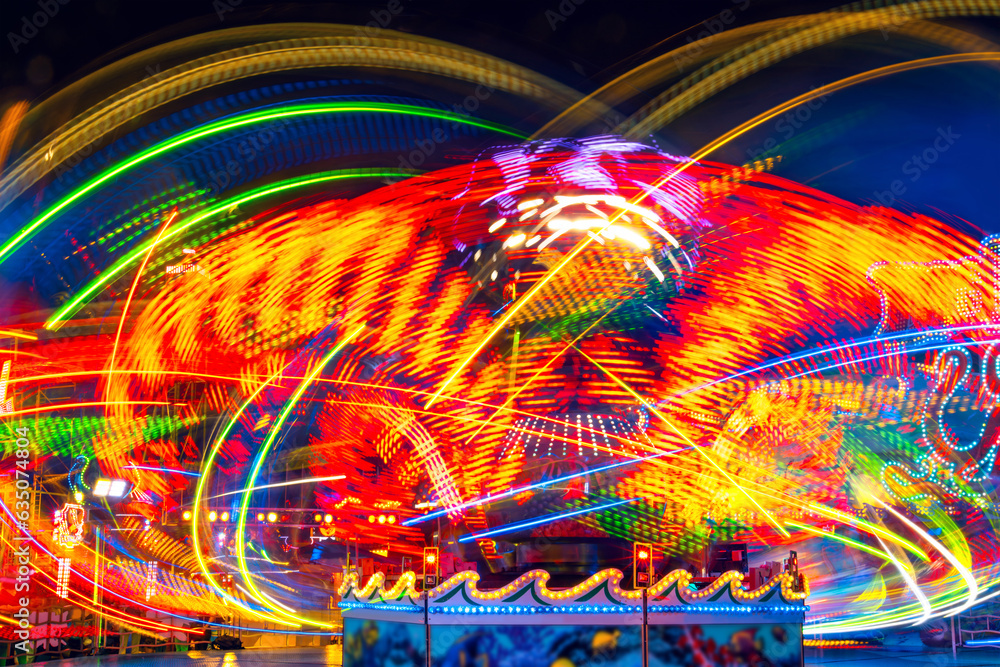 Merry-go-round at night with many colorful LED light traces. Long time ...