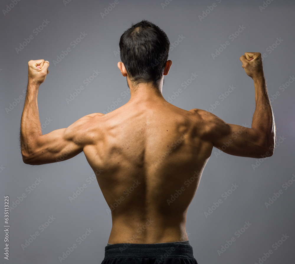 Muscular man showing muscles isolated on grey background. Biceps and ...