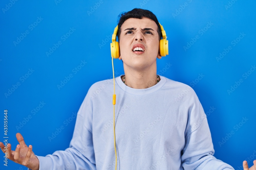 Non binary person listening to music using headphones angry and mad ...