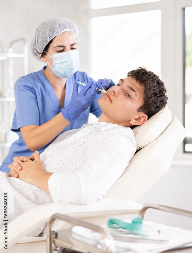 Female doctor conducting face revitalization procedure for young man ...
