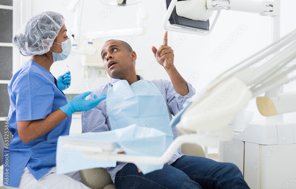 Qualified woman stomatologist pointing at teeth x-ray image on computer ...
