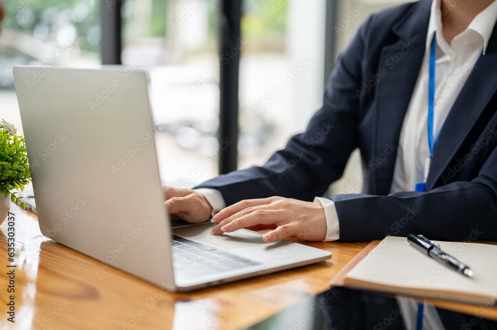 Close-up image of a businesswoman typing on a laptop keyboard, using ...
