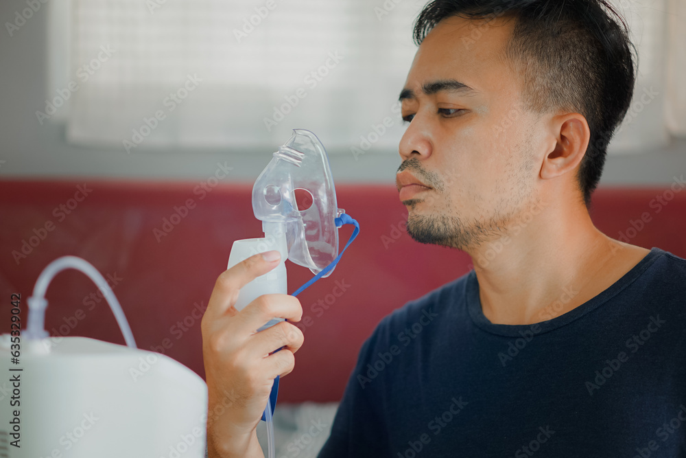 Asian boy wearing oxygen mask. man using asthma inhaler while sitting ...