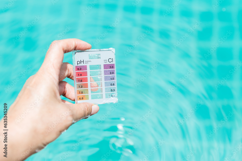 Mini water tester test kit in girl hand dipping in swimming pool water ...