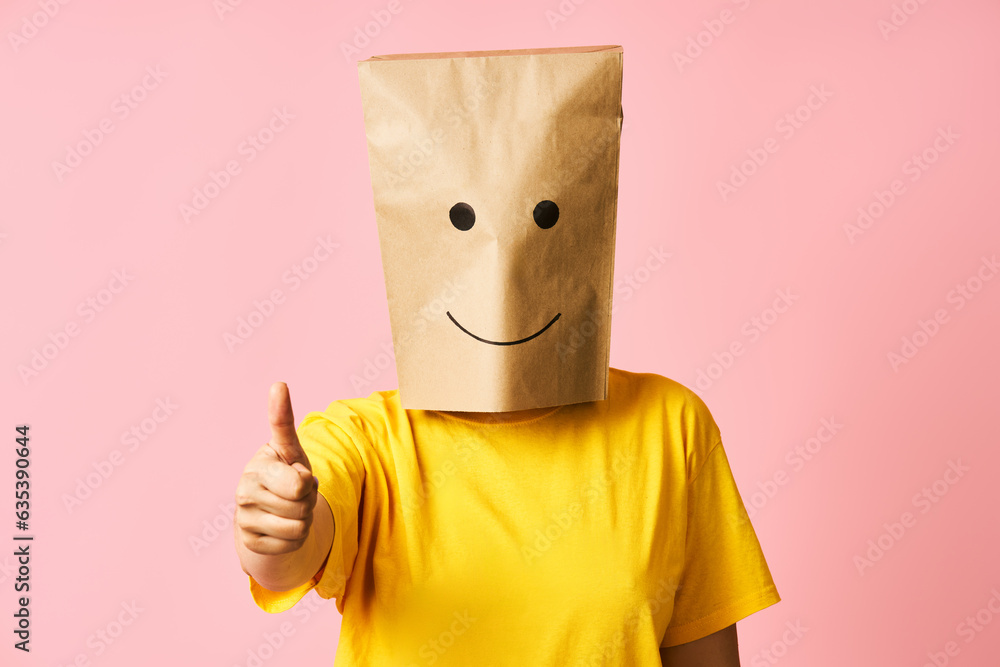 Woman wearing paper bag on head with smile emoticon icons face showing ...