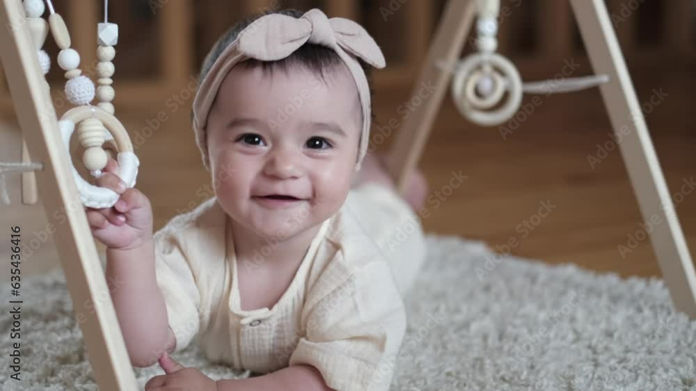 smiling baby girl on her tummy, extending her arms towards her ...