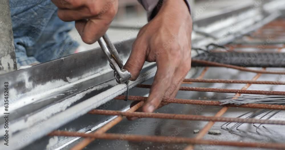 Reinforced concrete structures. Construction worker uses pilers tools ...