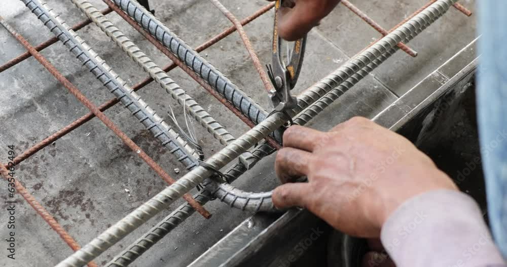 Reinforced concrete structures. Construction worker uses pilers tools ...