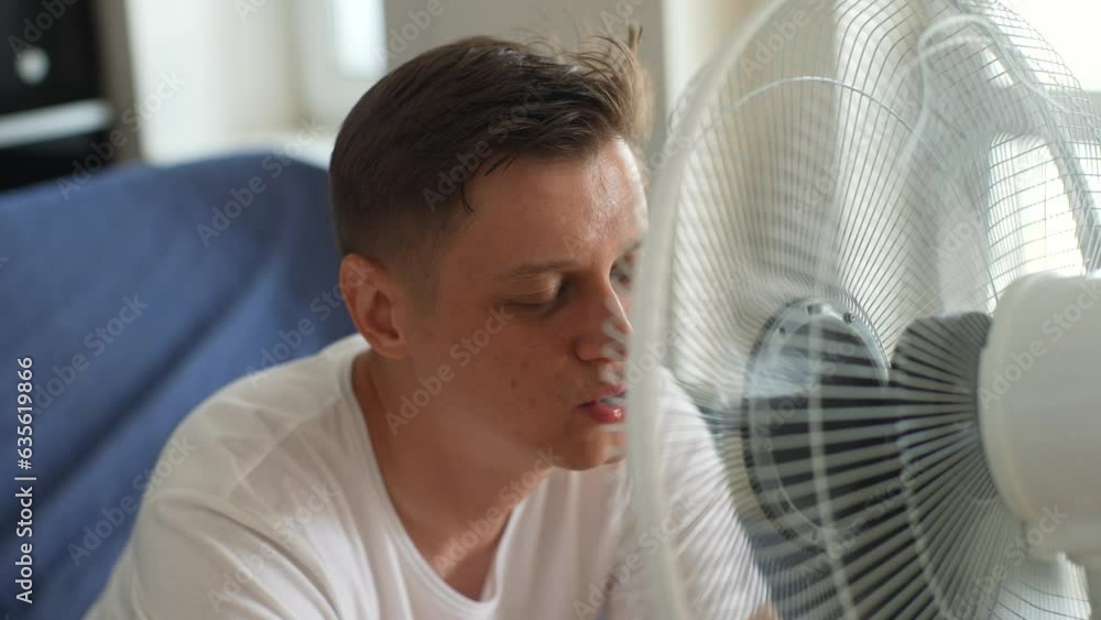 Tired man suffering from summer heat trying to cool off with eclectic ...