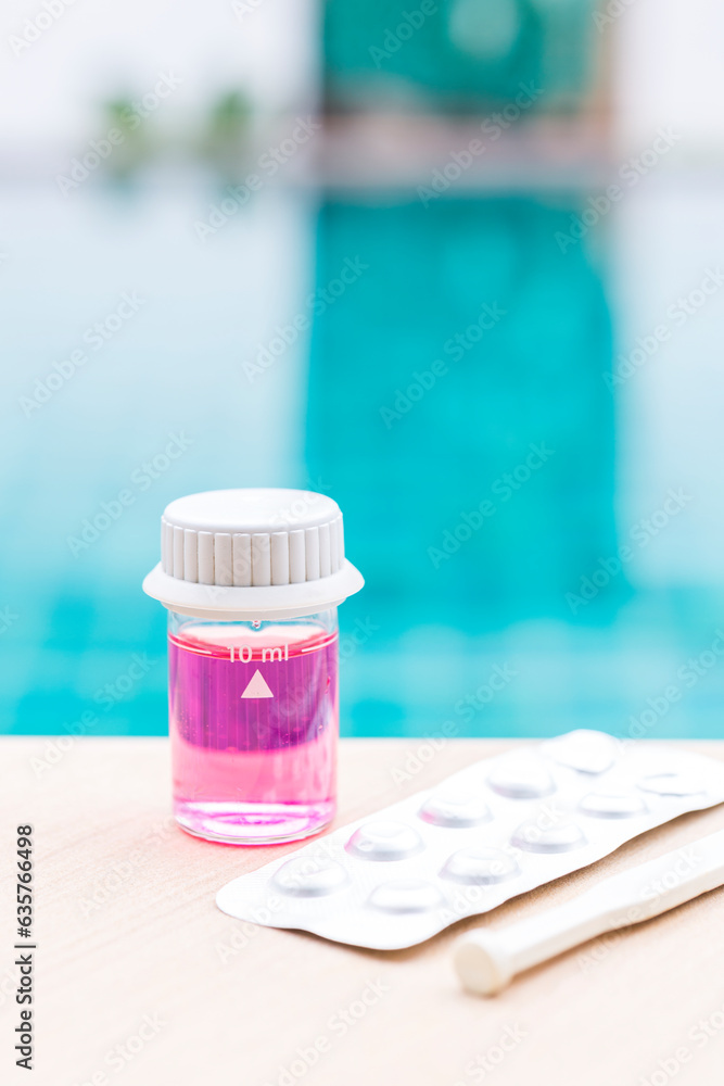 Pool water in glass vials with pH table reagents and stirring rod on ...