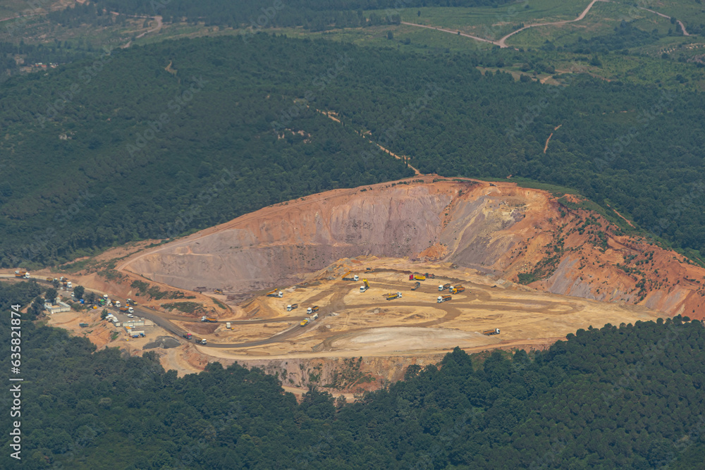 Aerial view from above of opencast mining quarry with lots of machinery ...